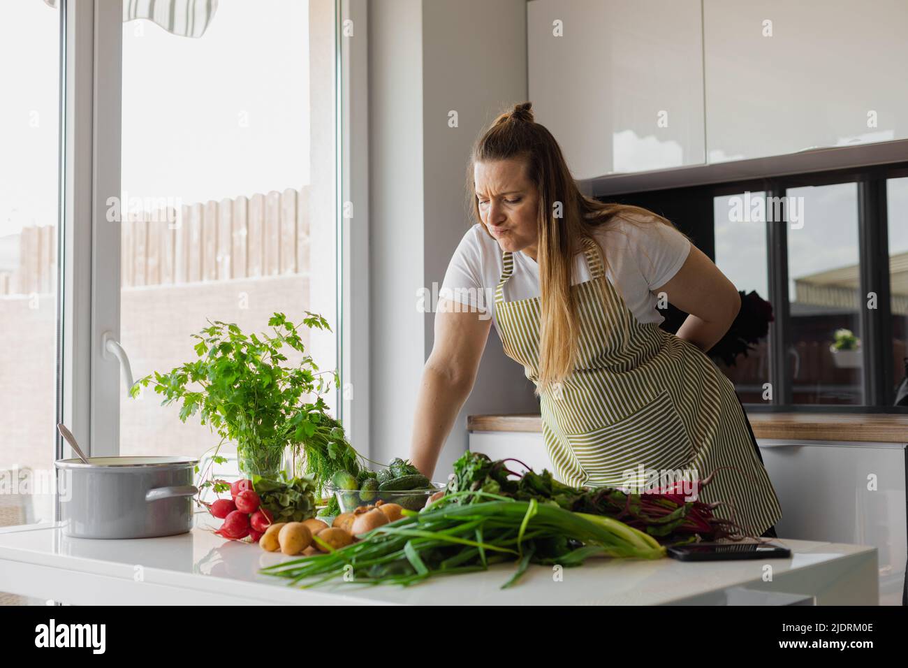 Plump, plus size blonde woman cooking healthy food in the kitchen ...