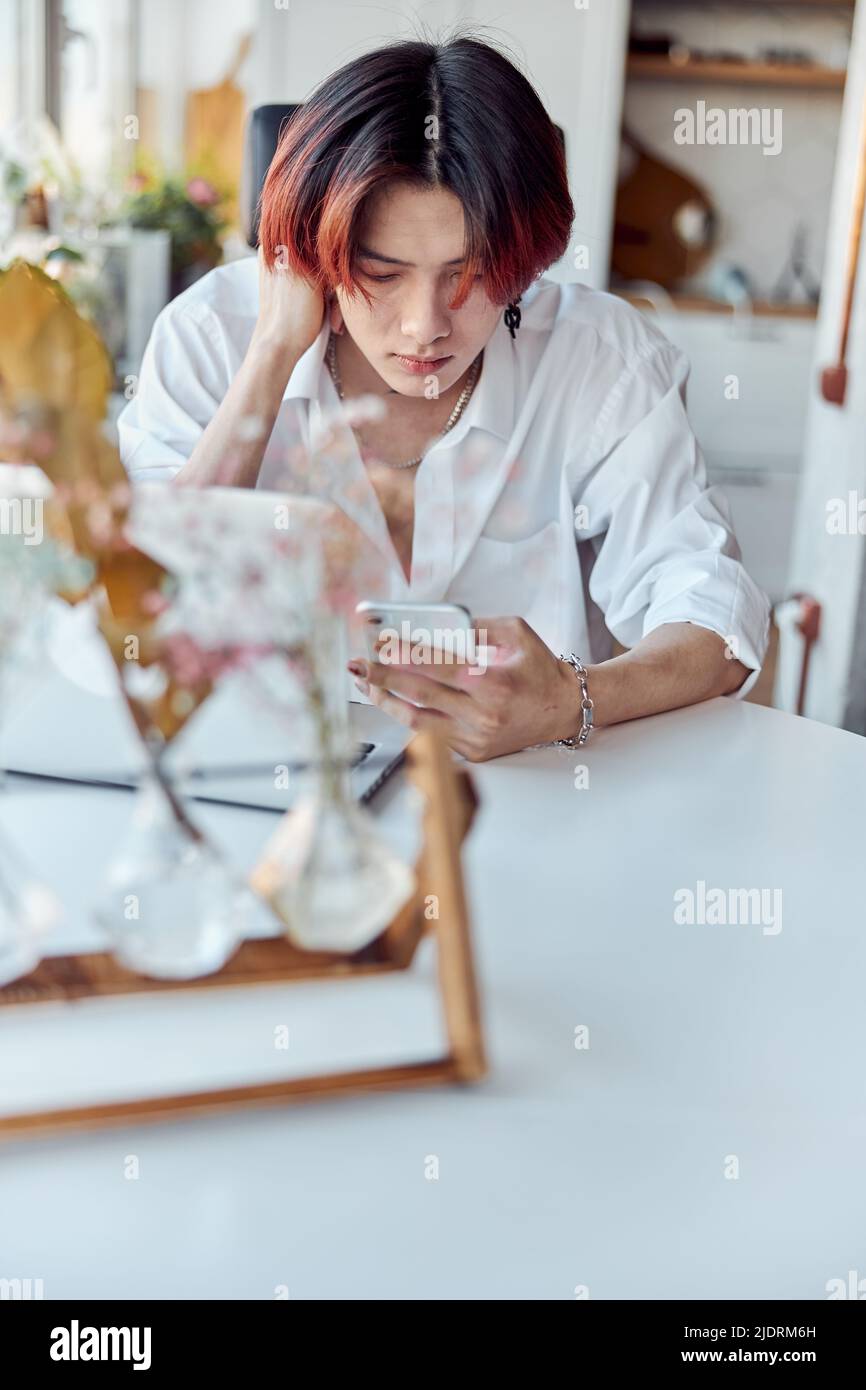 Serious Asian guy holding phone while chatting online Stock Photo - Alamy