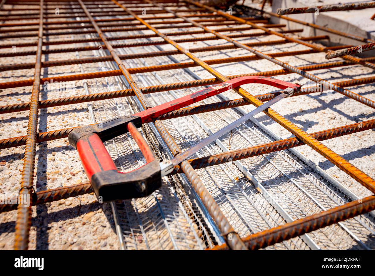 A hand hacksaw for metal set on rusty square reinforcing mesh that was ...