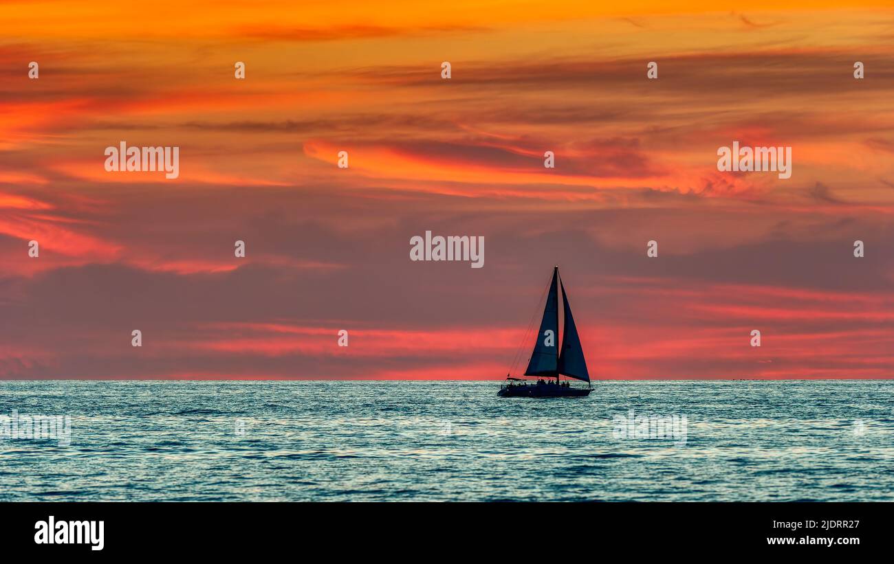 A Sailboat Sailing Along The Sea At Night With A Colorful Sunset Sky ...