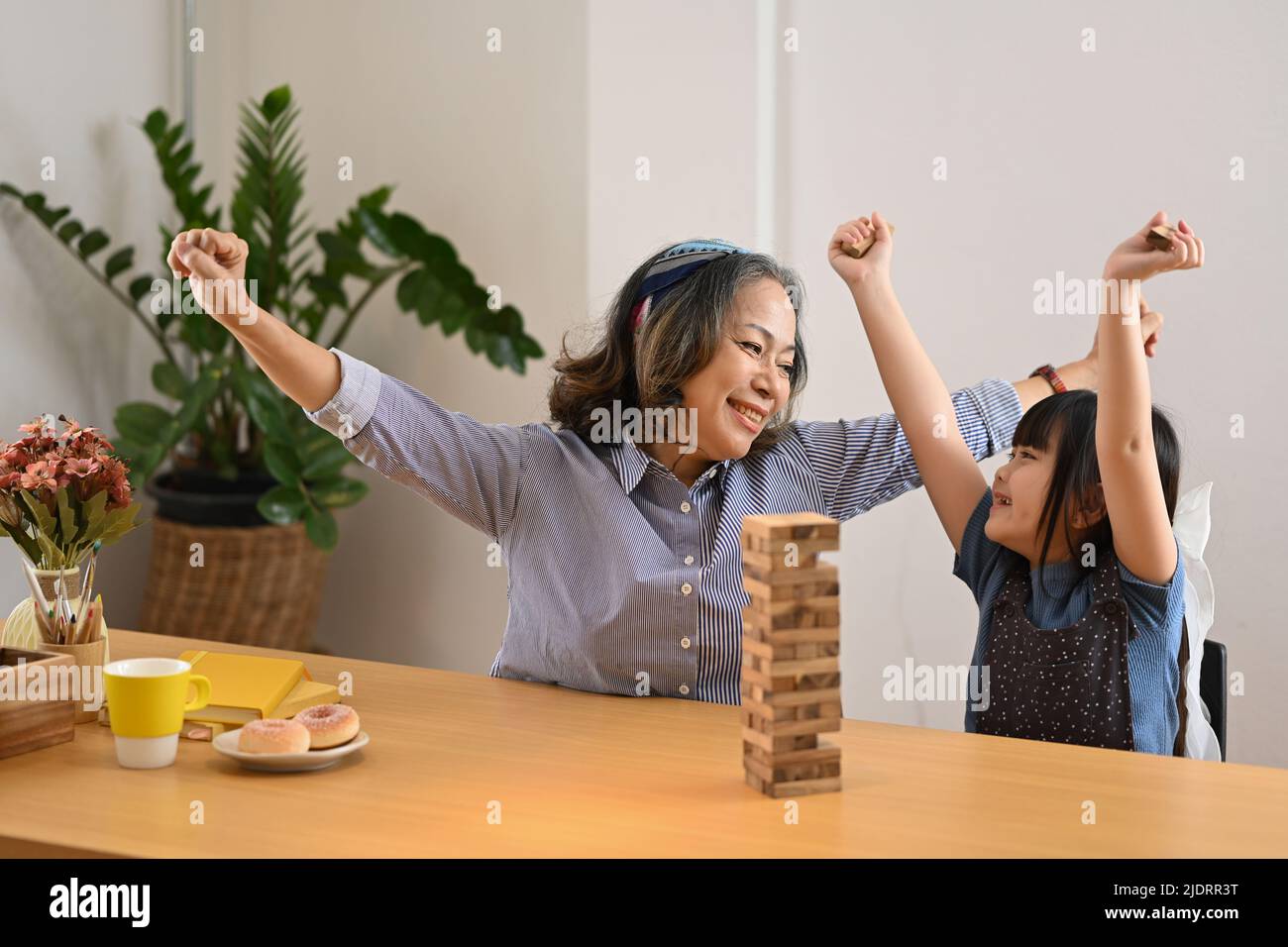 Overjoyed little asian girl and grandmother playing wood block stacking ...