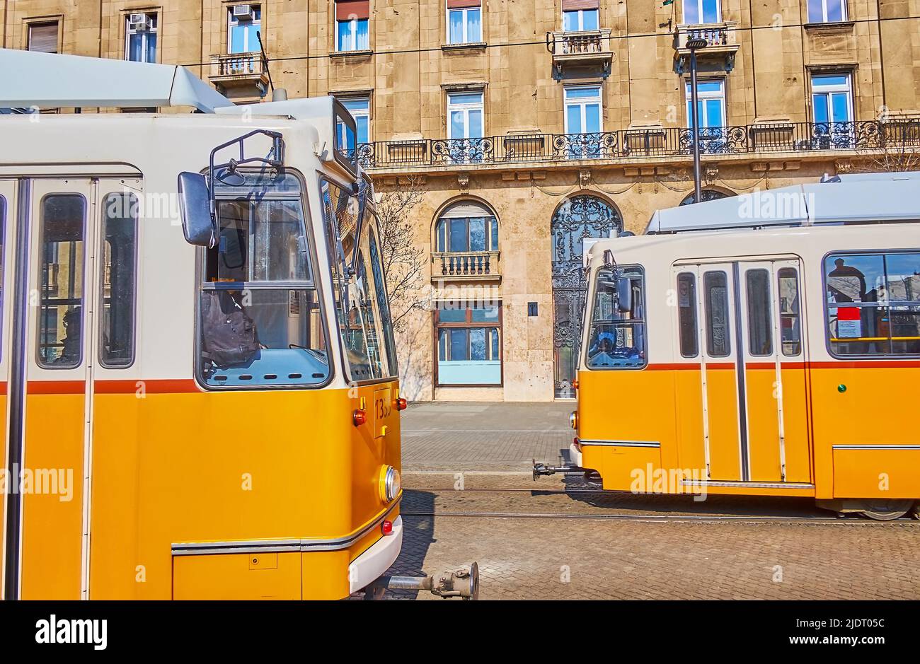 Two classic yellow trams, driving in different directions on Lajos ...