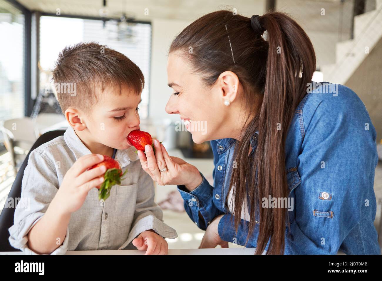 Mom feeds her little son a strawberry for health and vitamins Stock ...