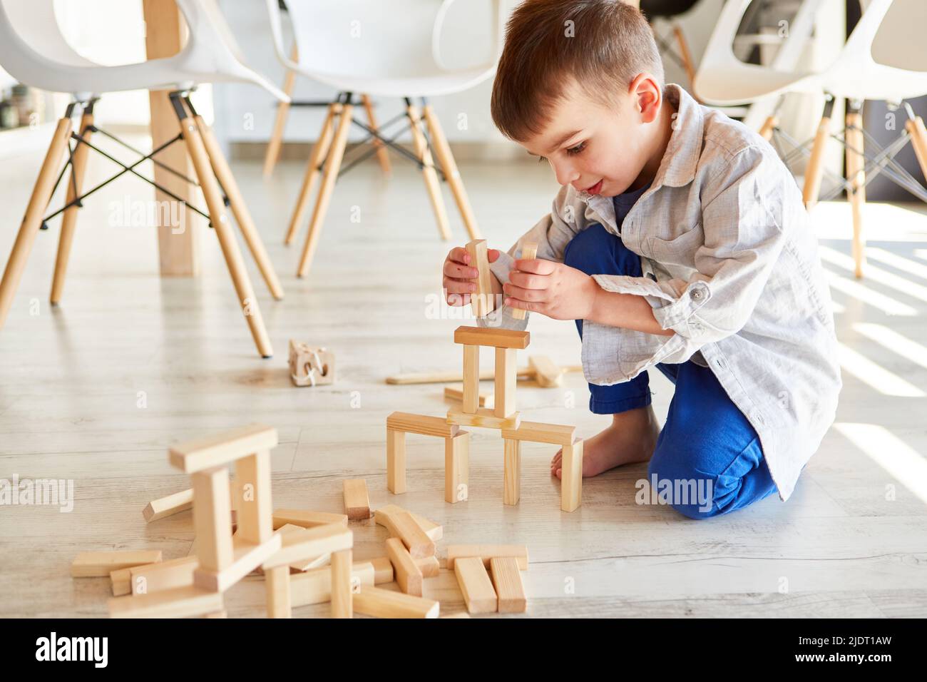 Little boy builds a tower of wooden blocks for balance and motor skills ...