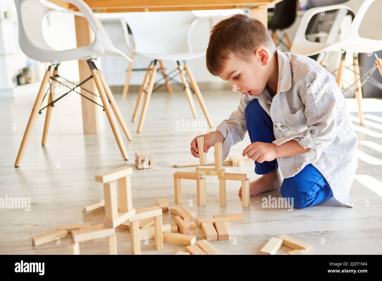 Little boy concentratedly stacking wooden building blocks while playing ...