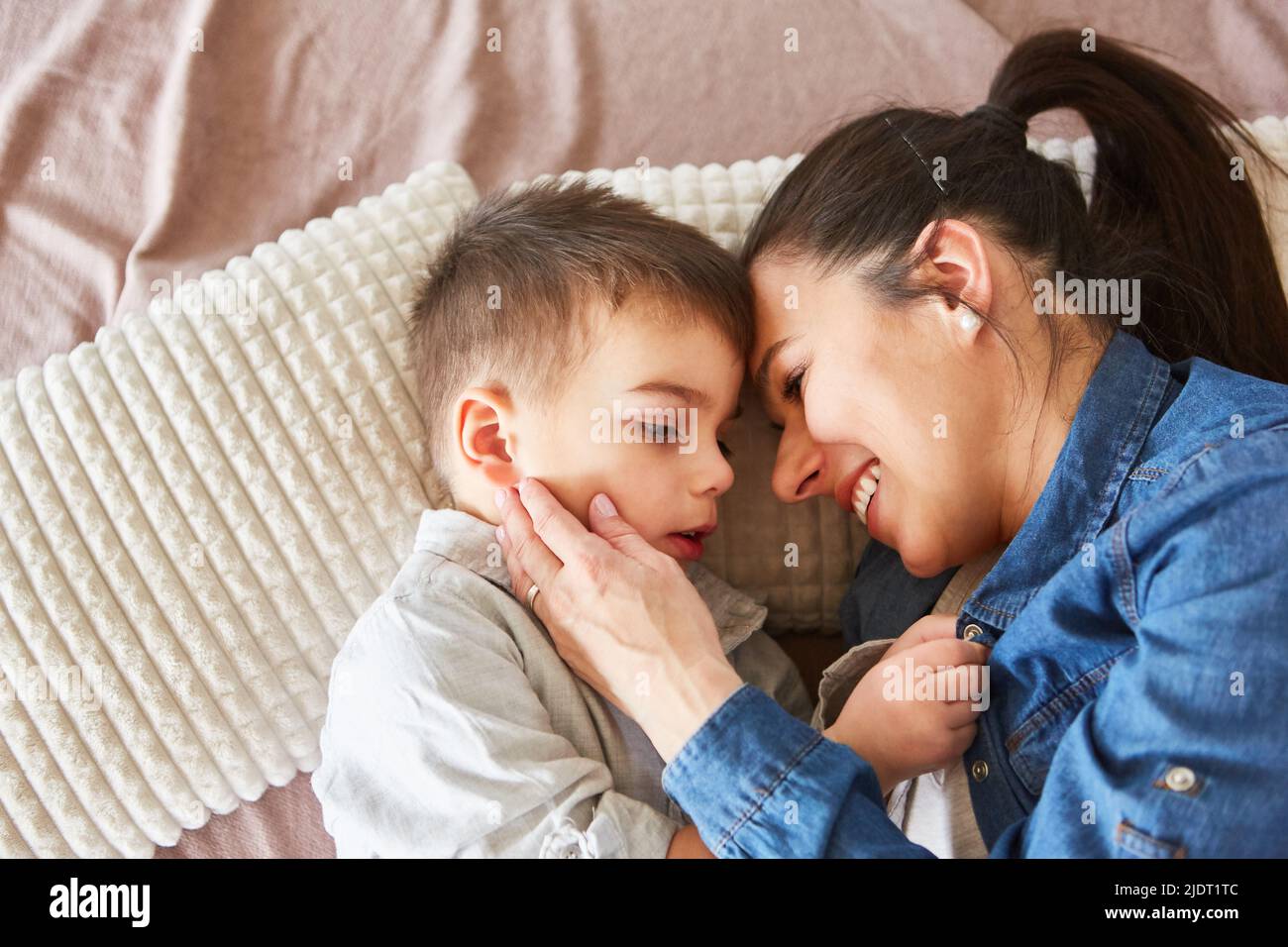 Happy mother lovingly cuddling with her son on the floor at home in the ...