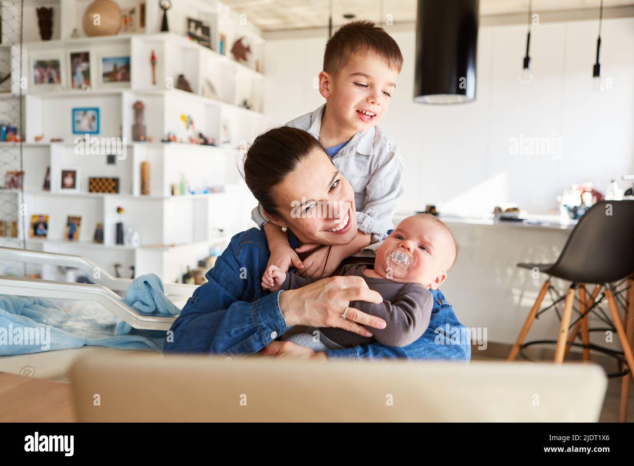 Happy mother with baby and toddler at computer streaming video in ...