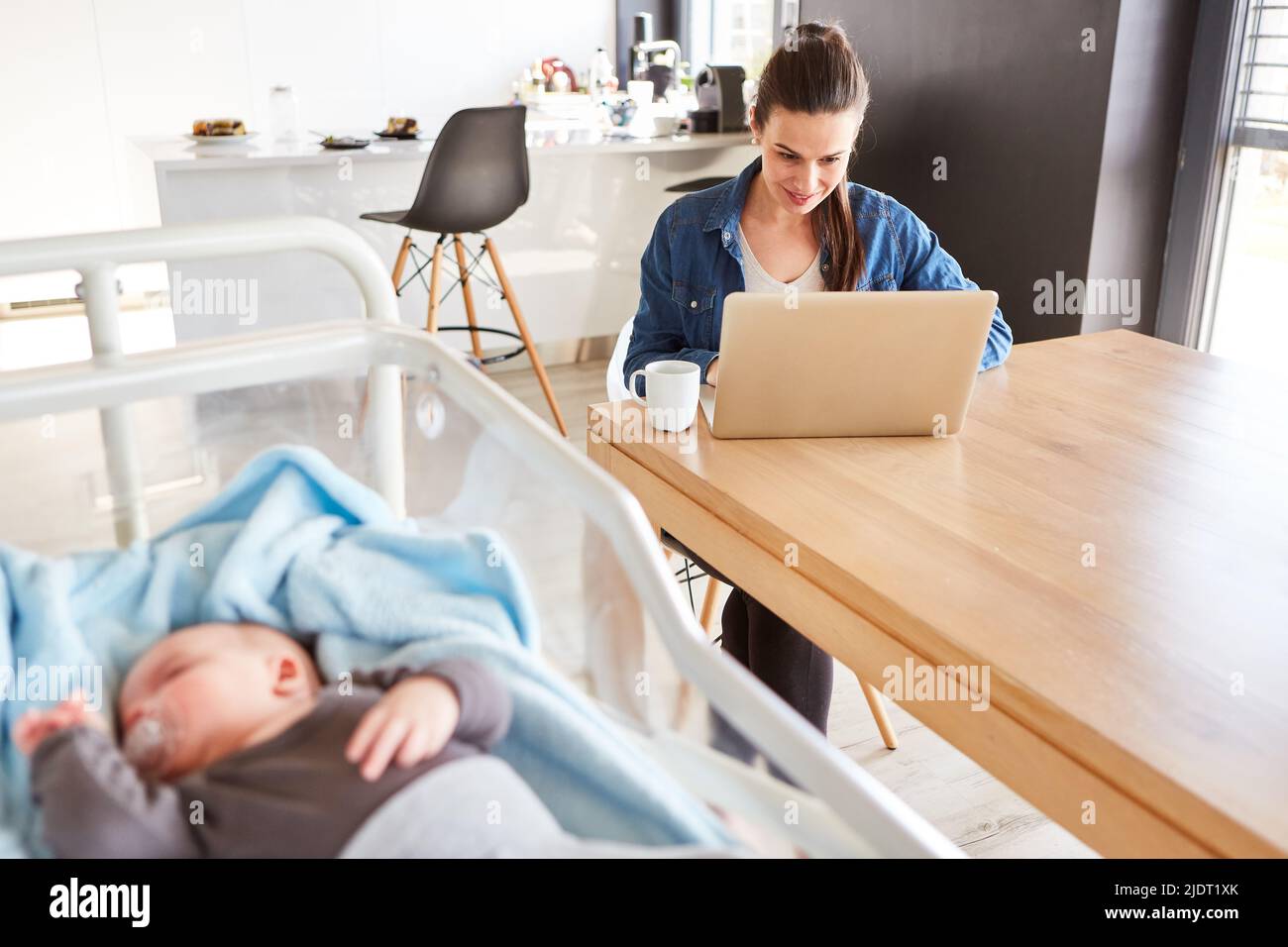 Single mother working on laptop pc in home office with baby in ...