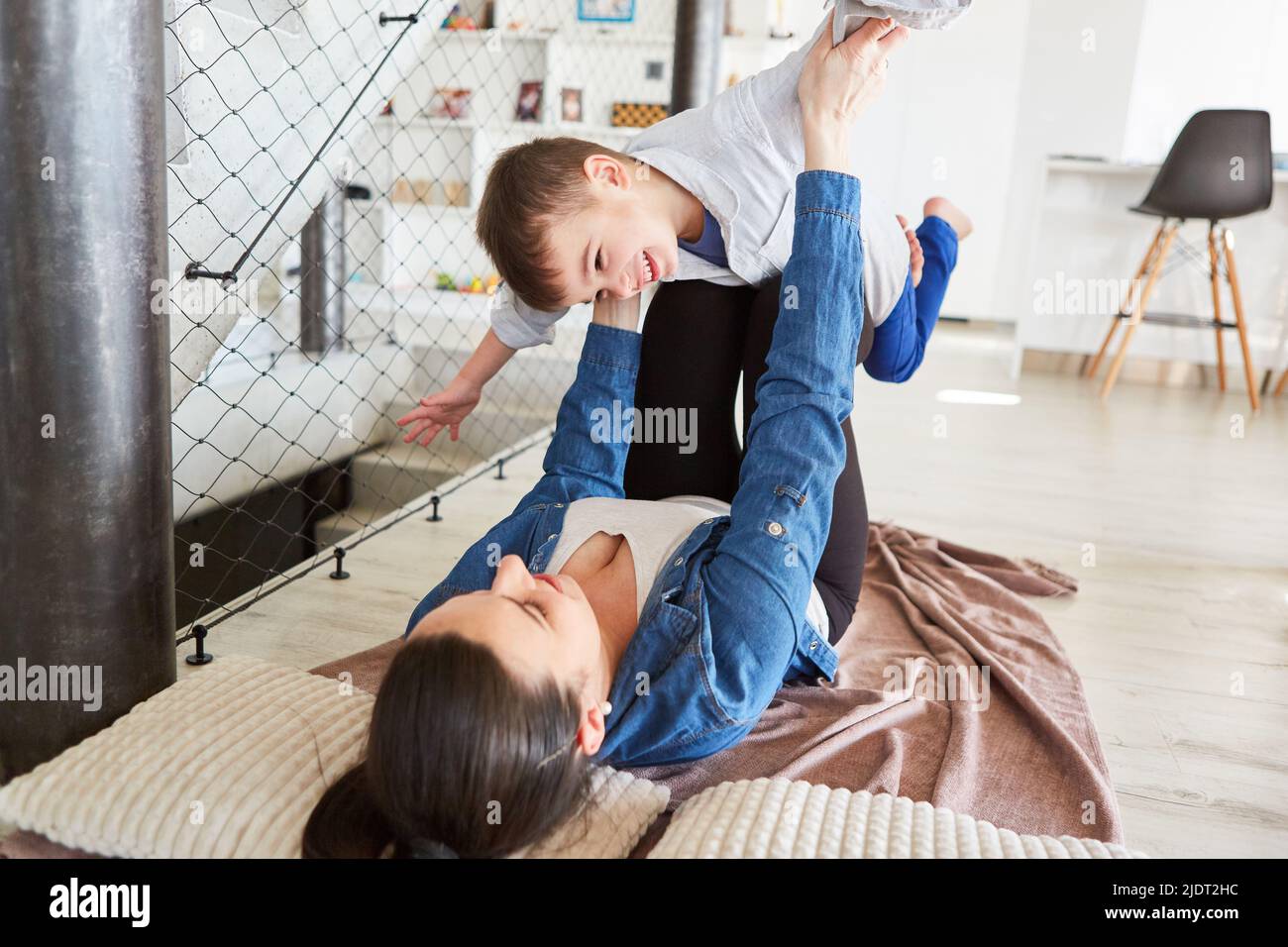 Mother romping with her laughing son at home in the living room Stock ...