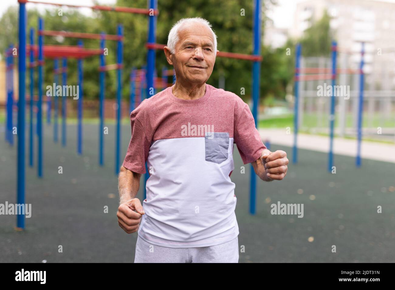 Old man running beside outdoor sports ground Stock Photo - Alamy