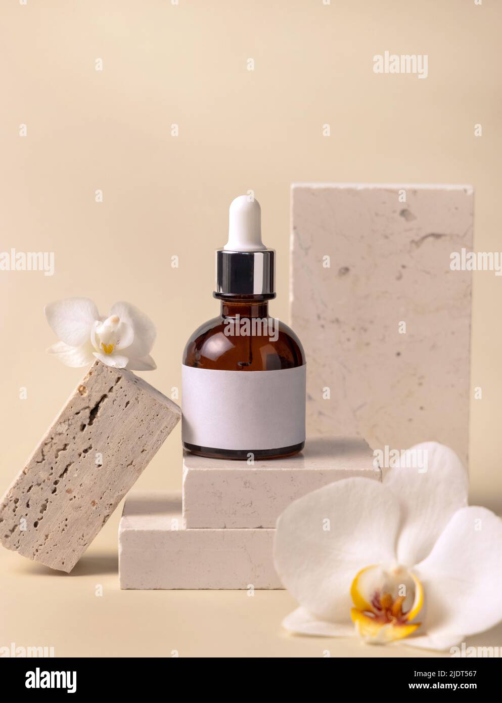 Brown glass dropper bottle on stone near white orchid flowers on light ...