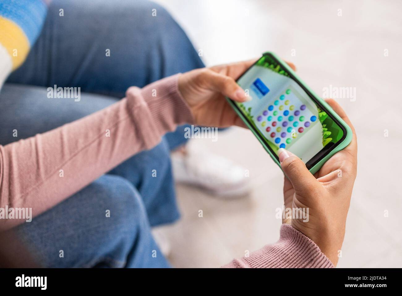 Young girl playing video game on mobile phone app - Focus on right hand ...