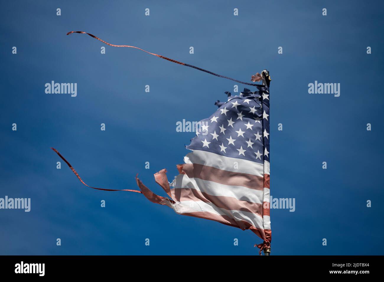 Worn and wind-torn American flag blowing against blue sky Stock Photo ...