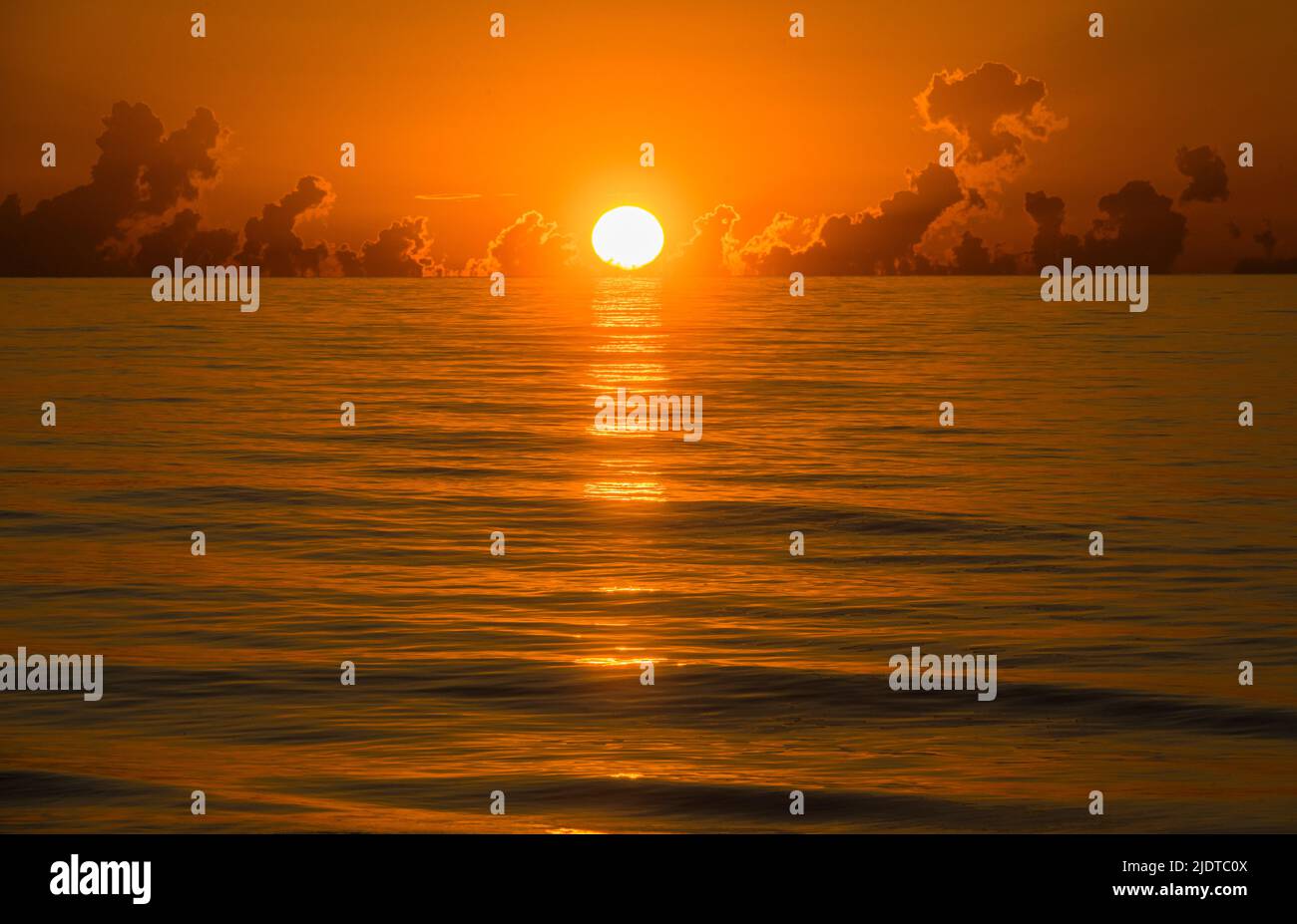 Sun rising above calm ocean Stock Photo - Alamy