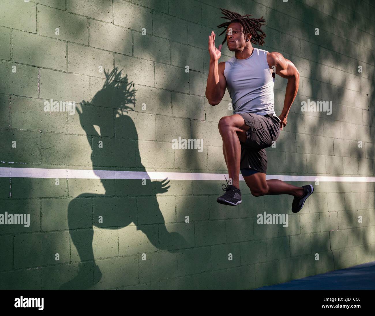 Athletic man jumping next to wall Stock Photo - Alamy