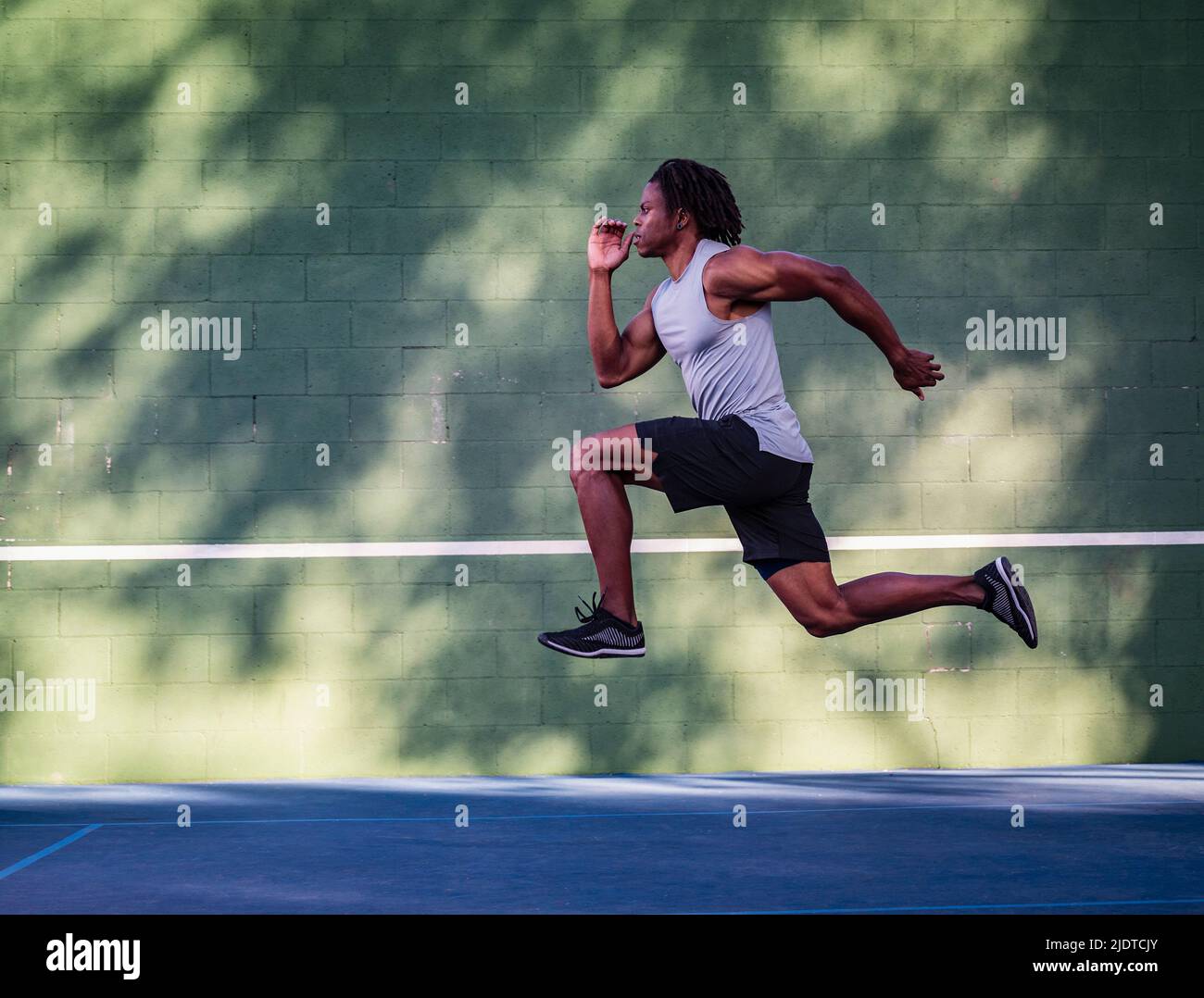 Athletic man running in front of wall Stock Photo - Alamy