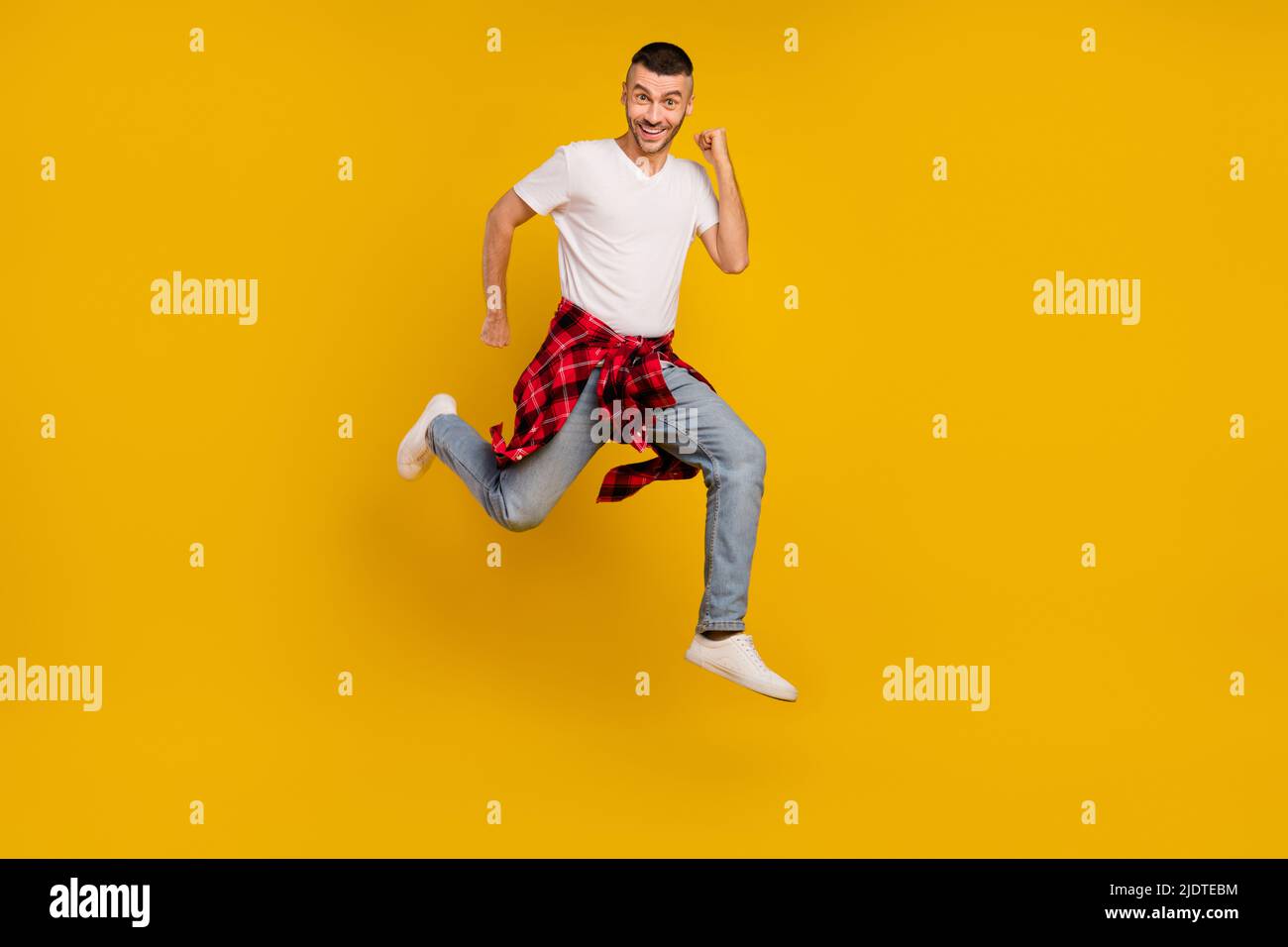 Full size photo of young happy man jump up runner wear checkered shirt ...