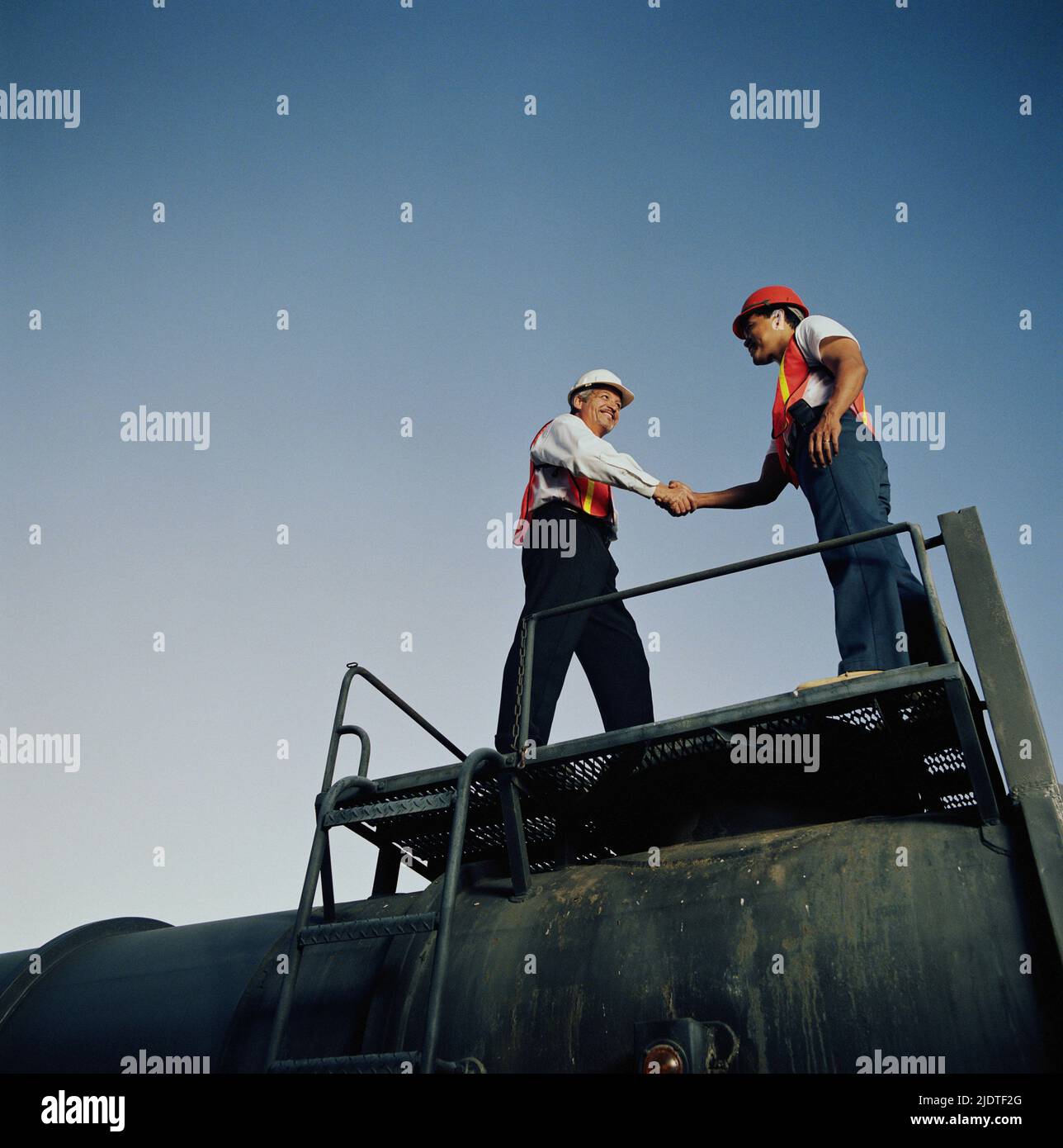 Two workers shaking hands on industrial platform Stock Photo - Alamy