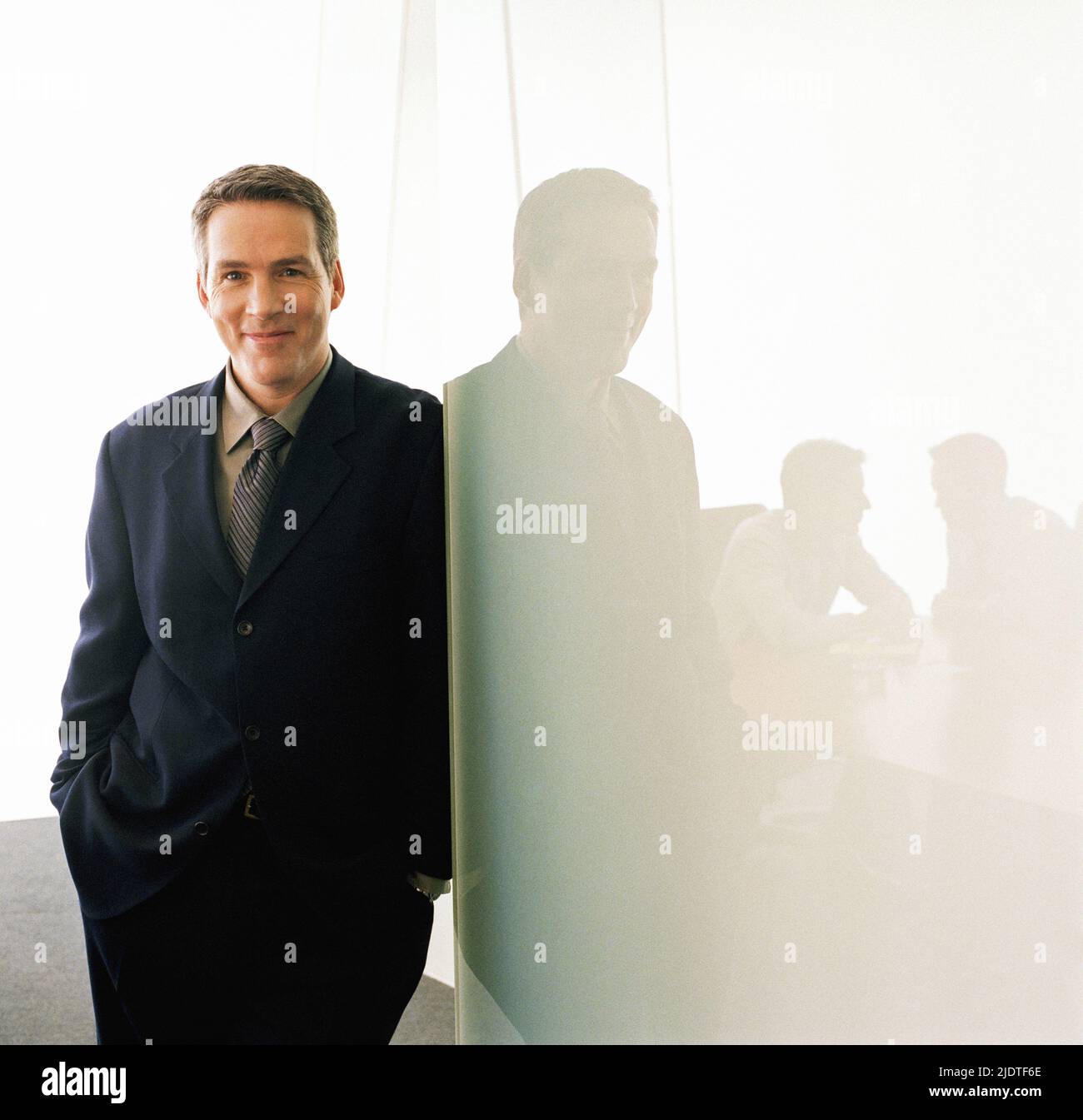 Portrait of business executive leaning against glass wall Stock Photo ...