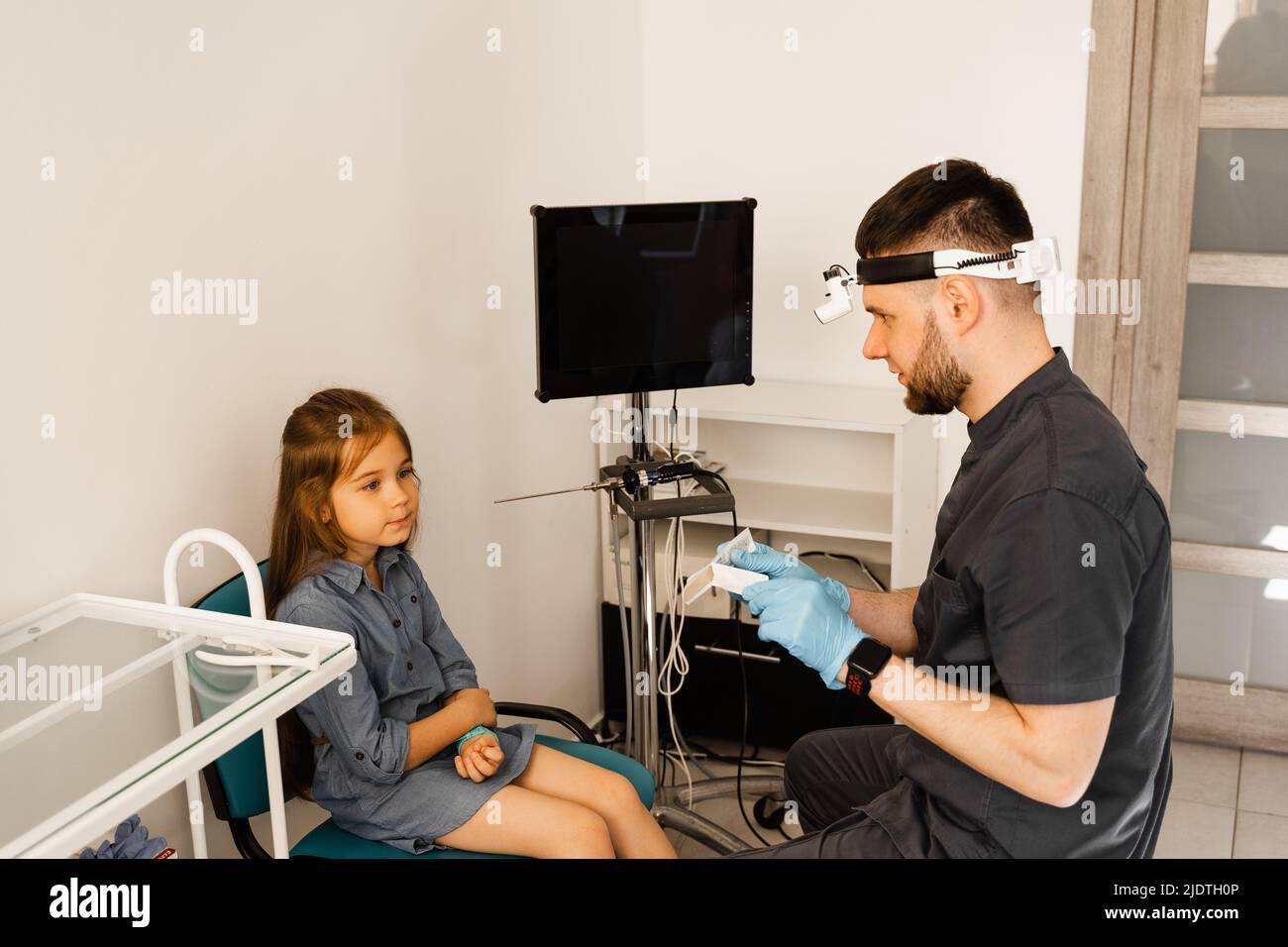 Oropharyngoscopy procedure. Otolaryngologist examines child throat with ...