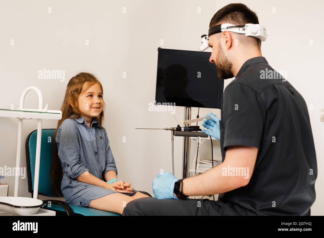 Oropharyngoscopy procedure. Otolaryngologist examines child throat with ...