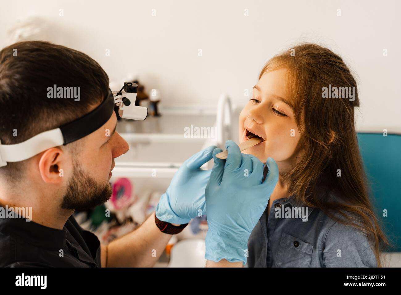 Oropharyngoscopy procedure. Otolaryngologist examines child throat with ...