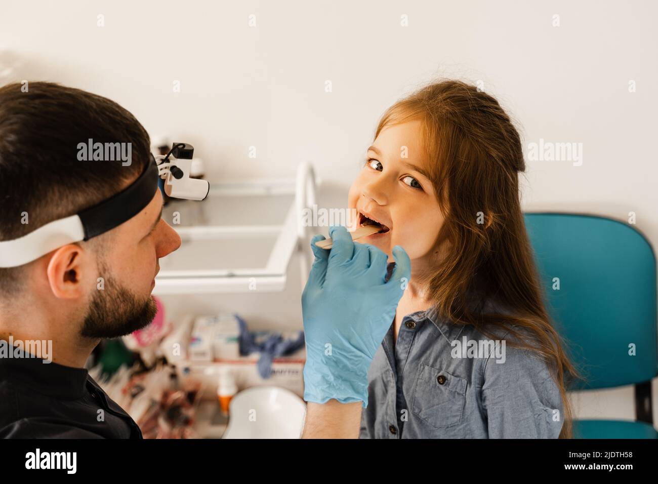 Oropharyngoscopy procedure. Otolaryngologist examines child throat with ...