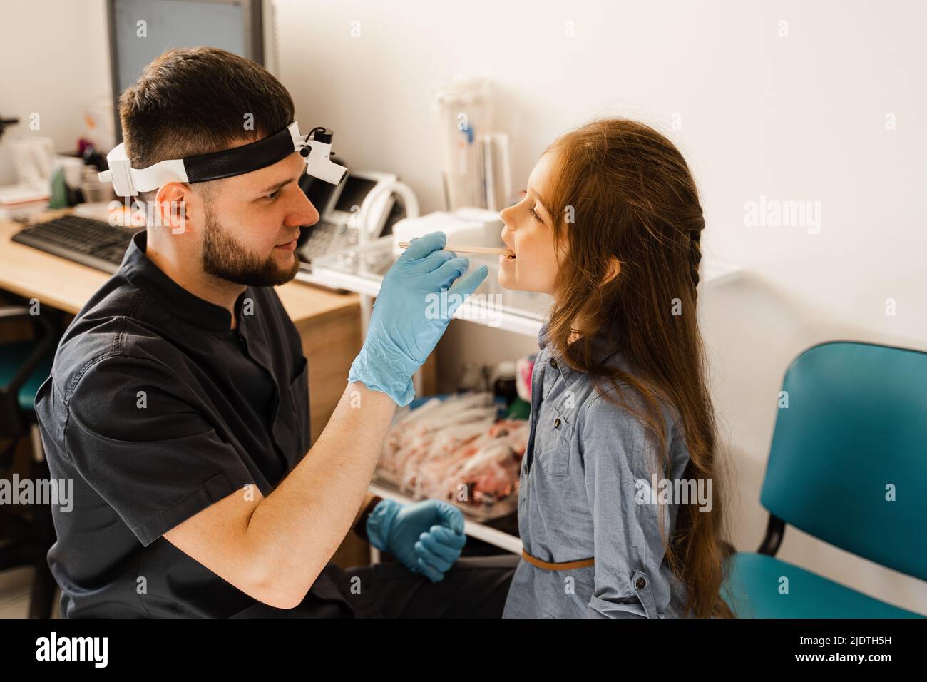 Oropharyngoscopy procedure. Otolaryngologist examines child throat with ...