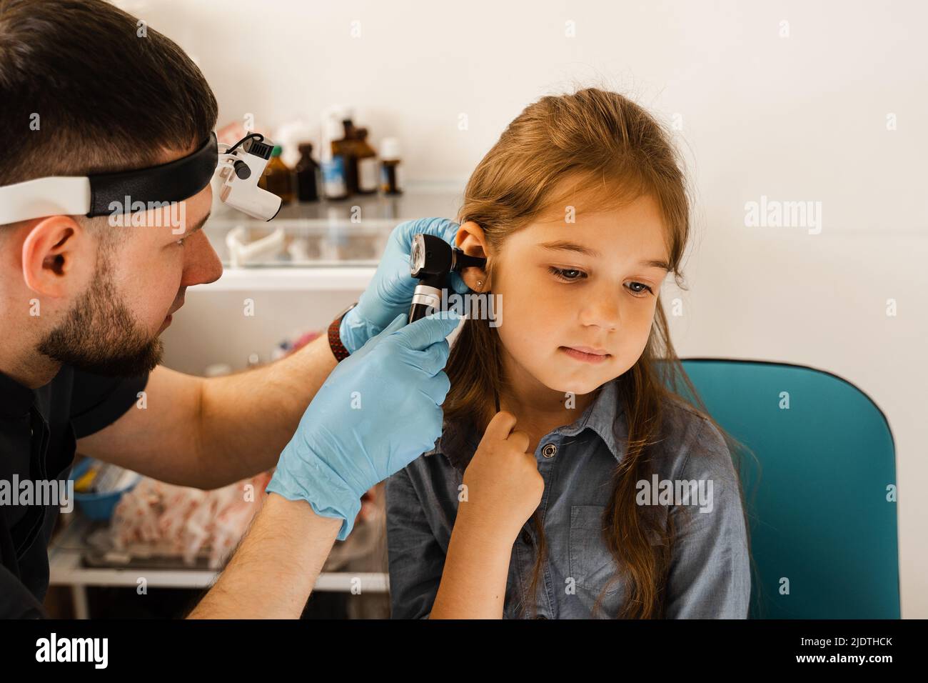 ENT doctor otolaryngologist looks through otoscope the ears of a little ...