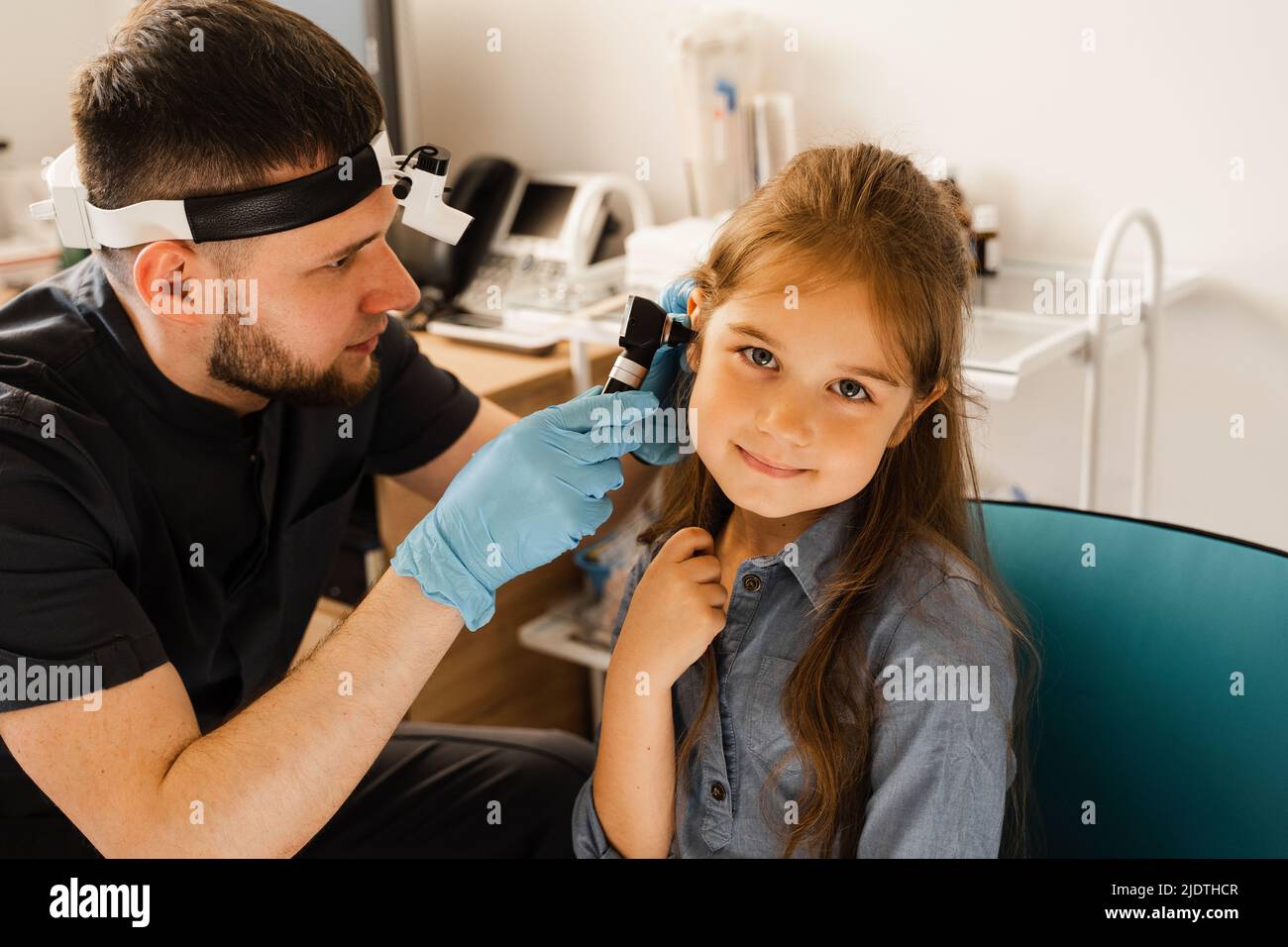 ENT doctor otolaryngologist looks through otoscope the ears of a little ...