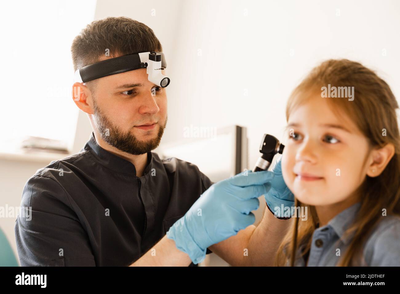 ENT doctor with otoscope. Otoscopy. Pediatrician otolaryngologist looks ...
