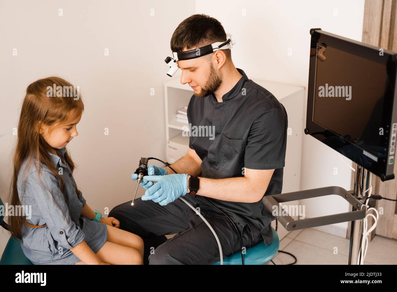 ENT doctor otolaryngologist with headlight showing to child endoscope ...