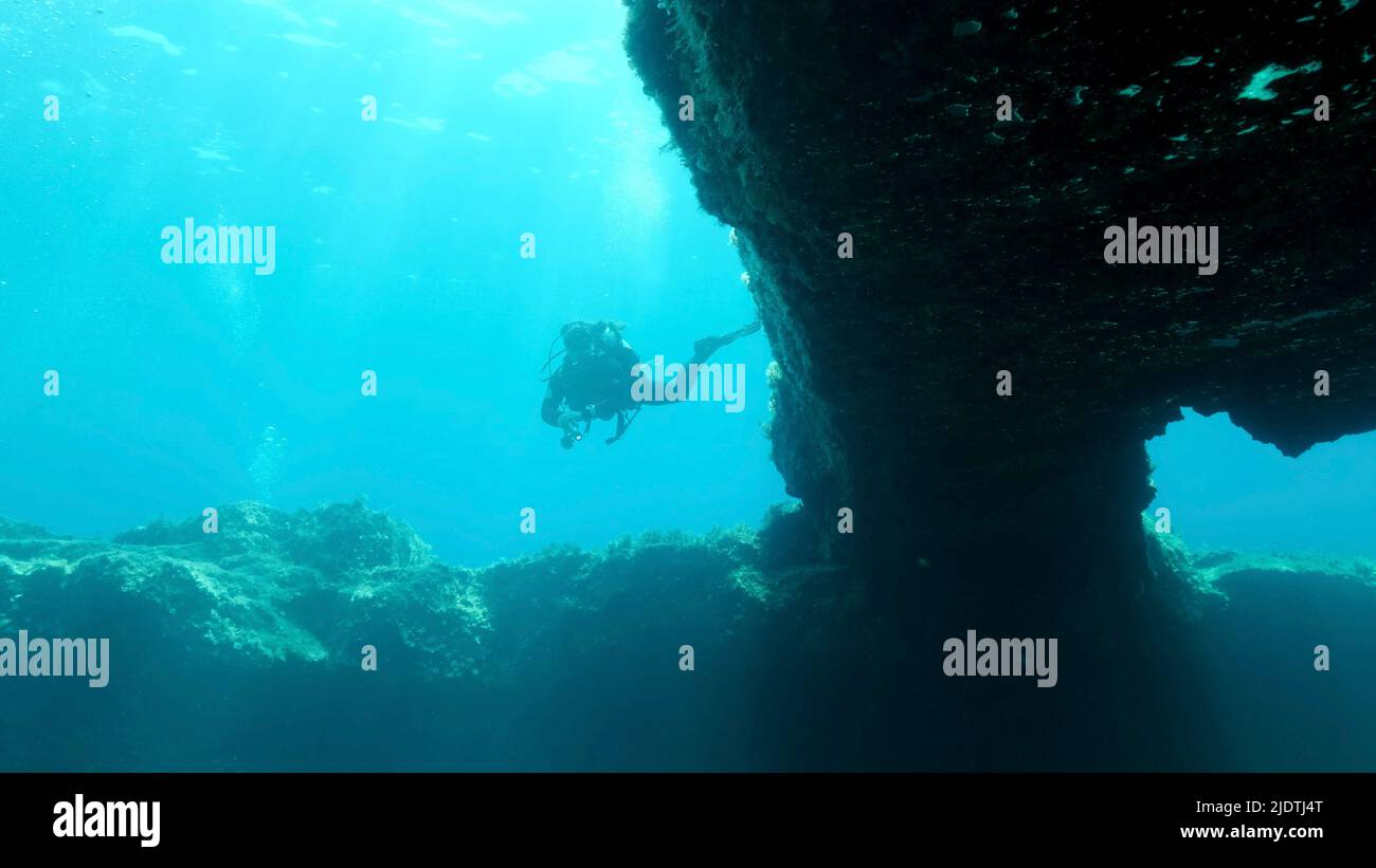 Female scuba diver swim near the exit from the cave. Cave diving in ...
