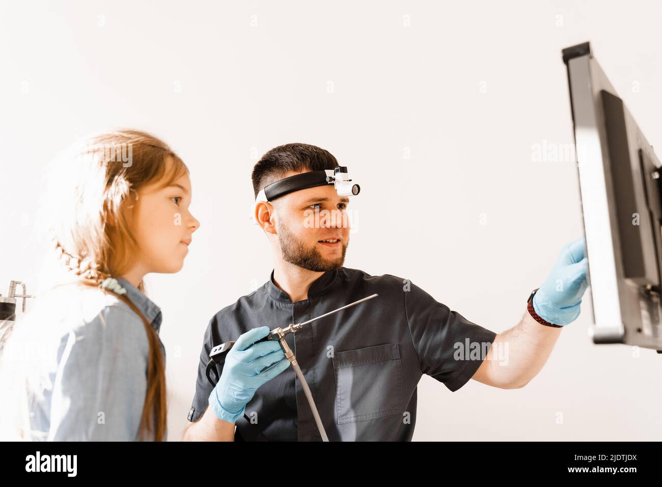 ENT doctor otolaryngologist with headlight showing to child endoscope ...
