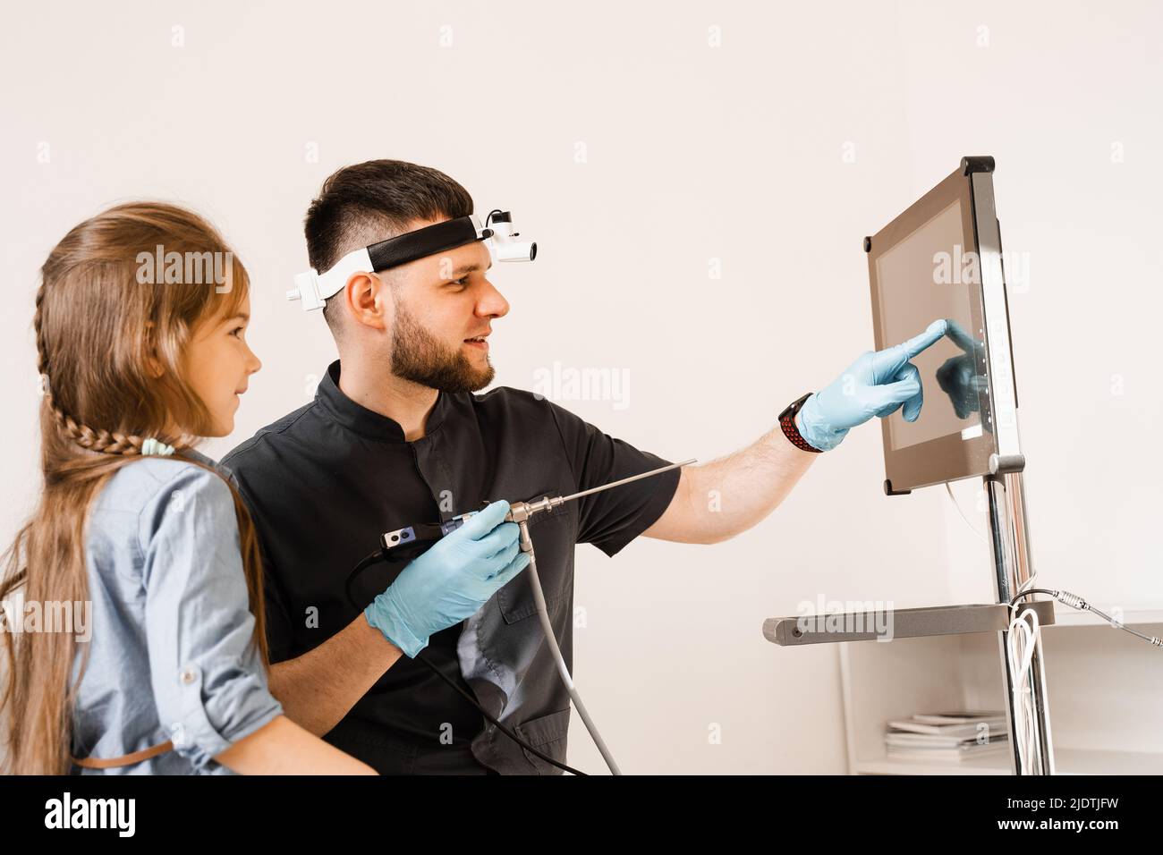 ENT doctor otolaryngologist with headlight showing to child endoscope ...
