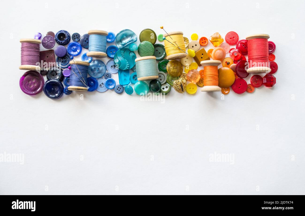 A lot of buttons and reels with colorful threads, laid out on a white ...