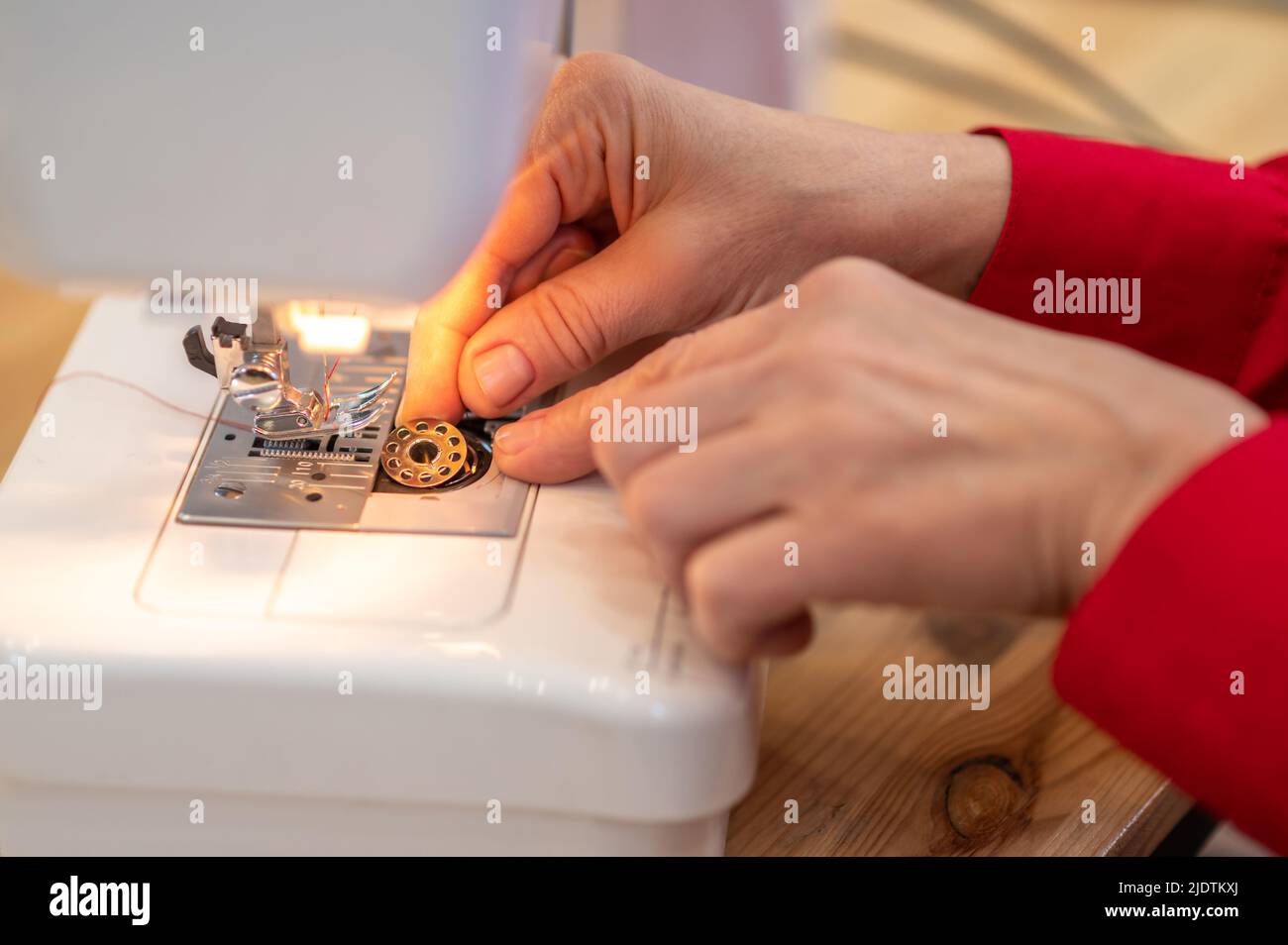 Hands installing spool in sewing machine Stock Photo - Alamy