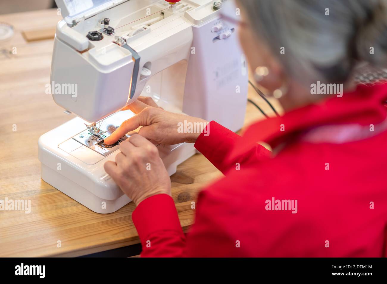 Back view of woman setting up sewing machine Stock Photo - Alamy