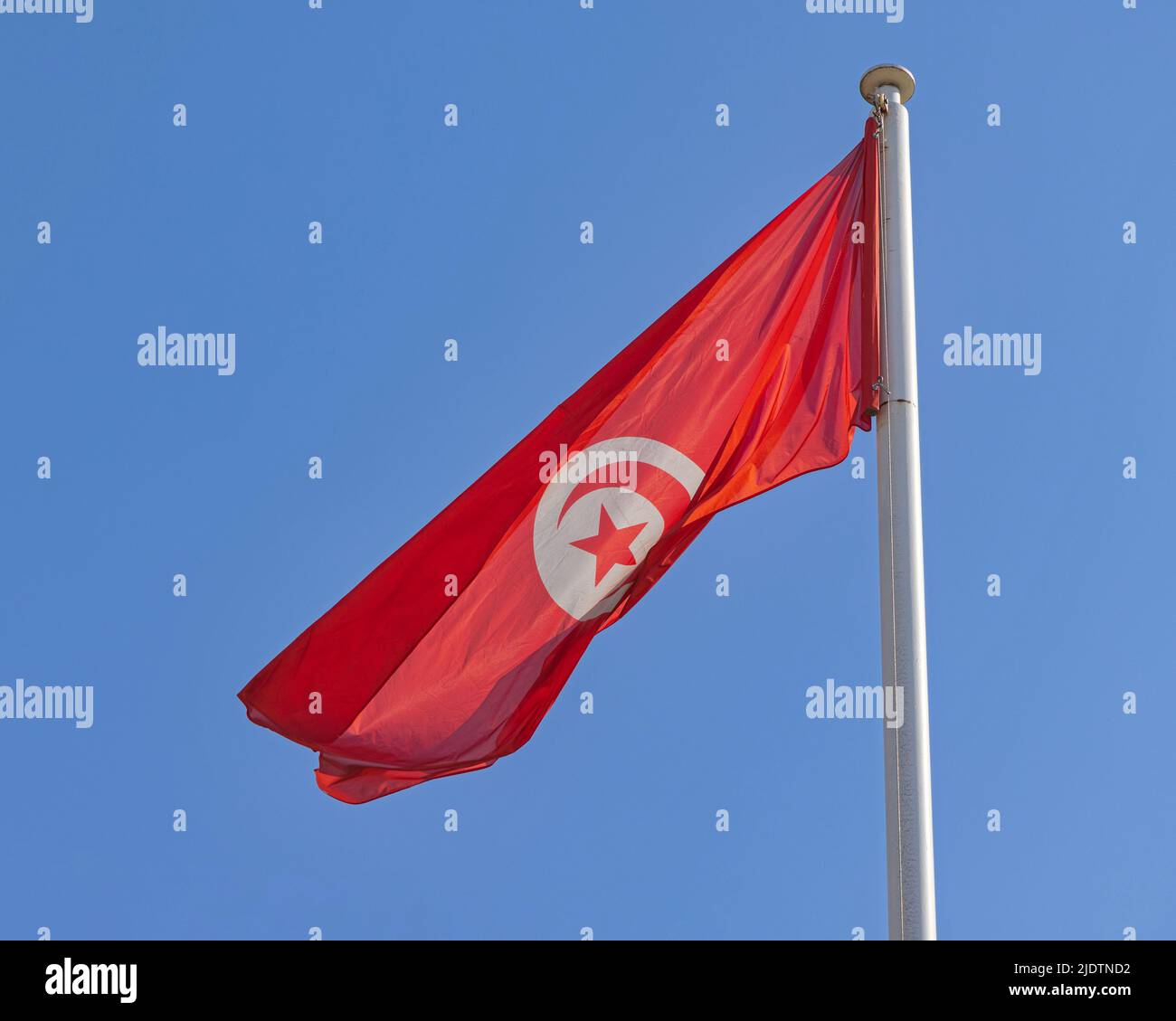 New Bright Red Flag of Tunisia at Clear Blue Sky Stock Photo - Alamy