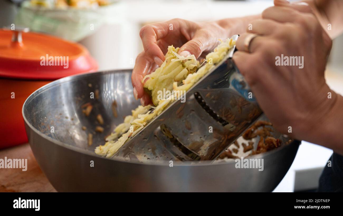 Closeup view of a woman grating an apple using a steel grater to ...