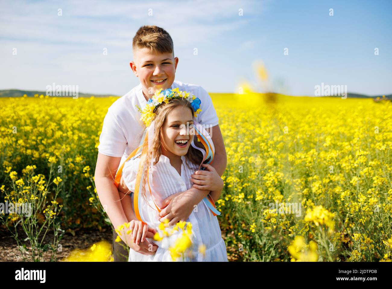 Brother hugs sister with Ukrainian wreath and bouquet of flowers in ...