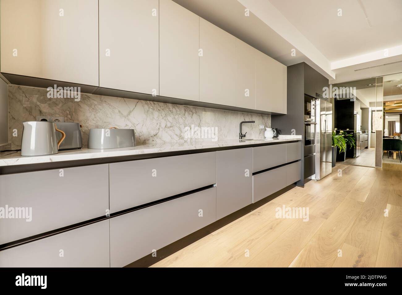 Wall of a kitchen with plain white base units and gray base units with ...
