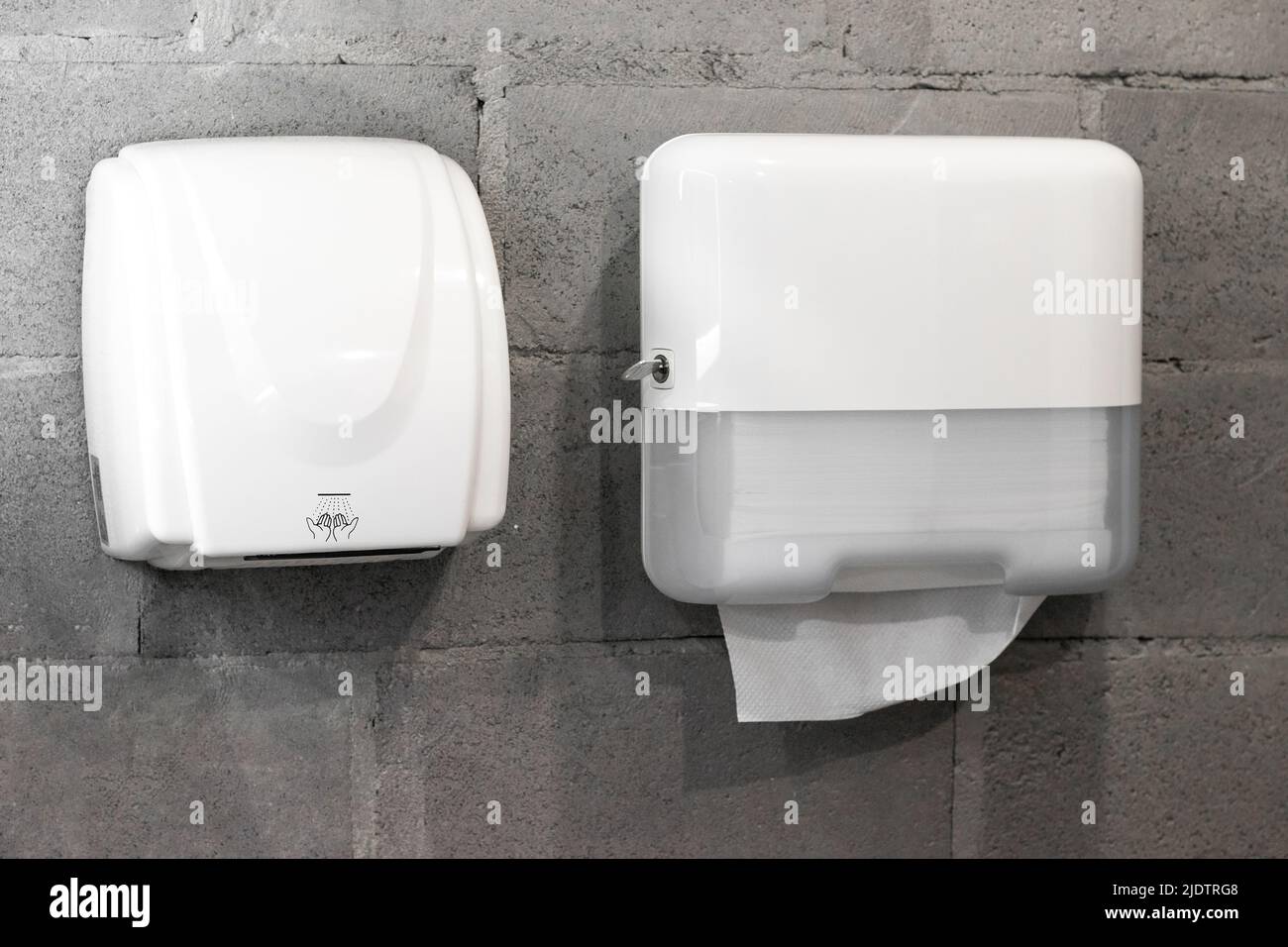 Paper towel dispenser and hand dryer on concrete wall on modern stylish ...
