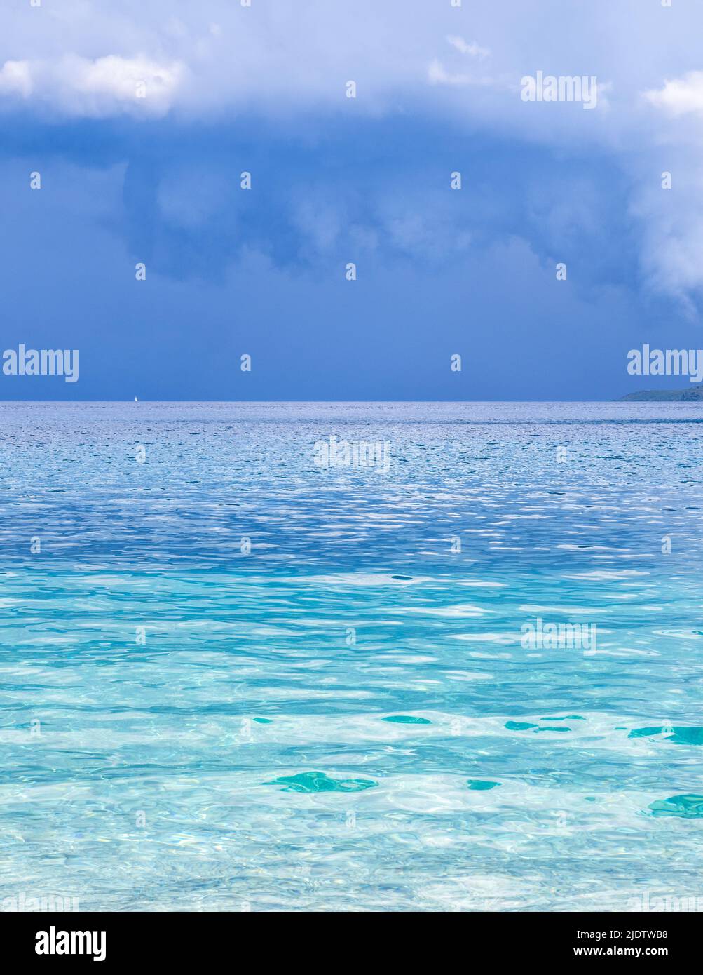 Turquoise sea against dark grey clouds with boat on the horizon at ...