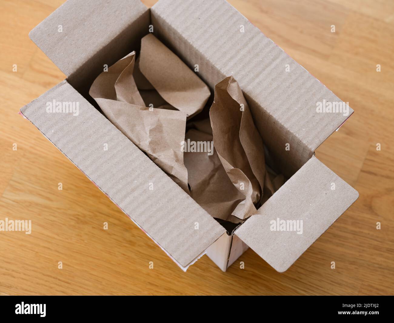 A cardboard box with some paper inside on parquet floor Stock Photo - Alamy