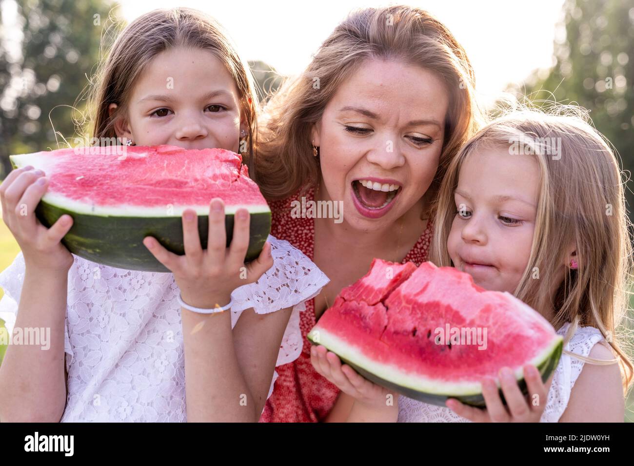 portrait of mom with cute daughters have fun while eating a slice of ...