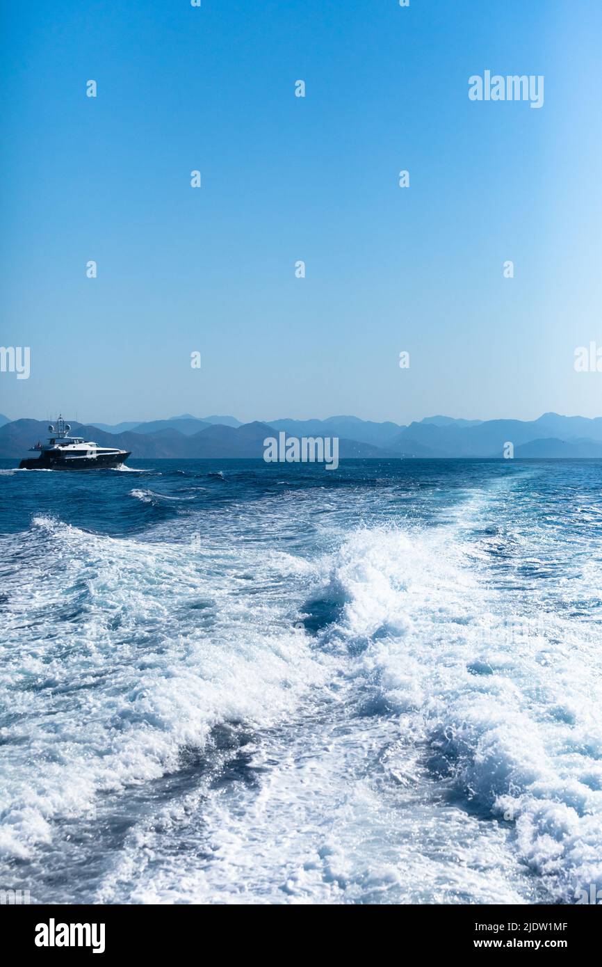 View from a high-speed ship on the blue sea with a mountainous coast in ...