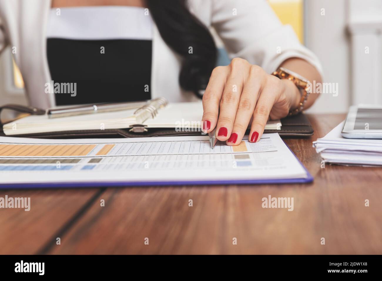 Closeup of woman's hand holding a pen on notebook. Freelance journalist ...