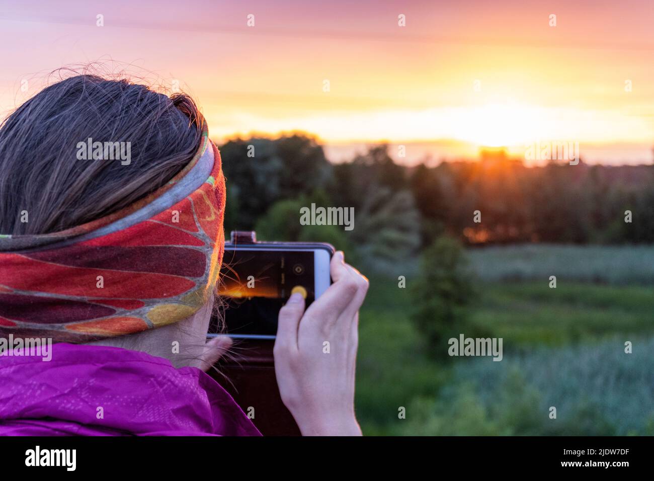 The photo of a girl from behind taking photo of a sunset Stock Photo ...