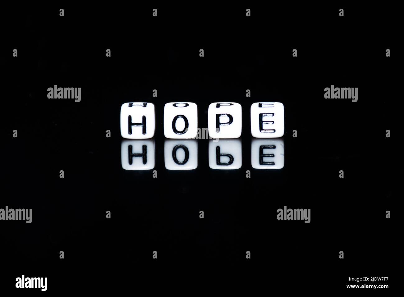 The word of "HOPE" making from little acrylic cubes in black background ...